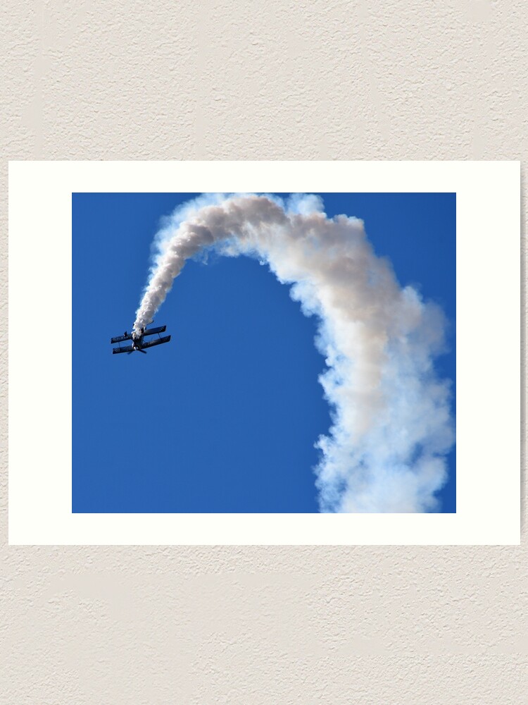 " Pitts Model 12 stunt byplane performing with smoke trail and blue sky ...